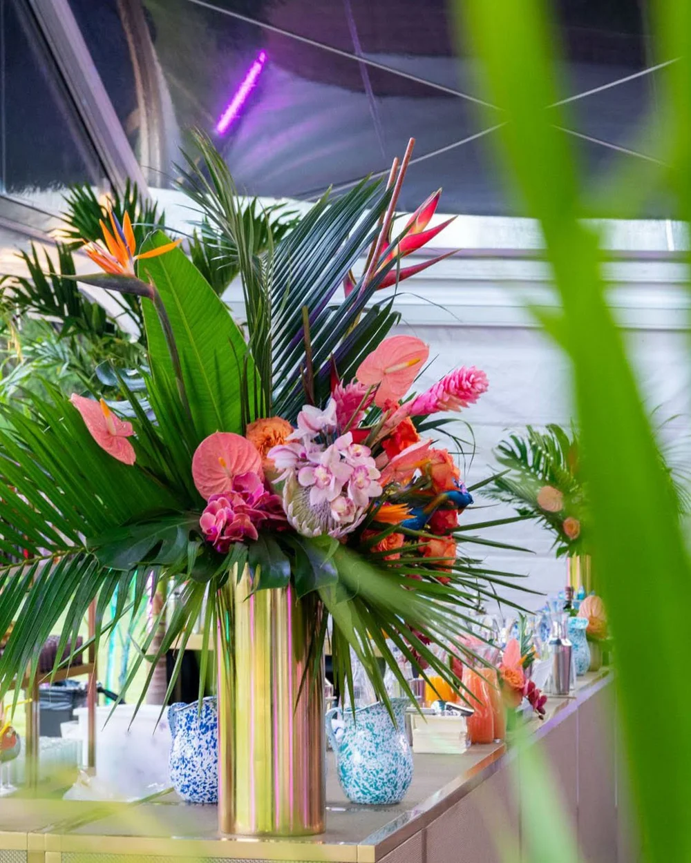 A Palm Royale party with palms, floral and fruit arrangements and a ...