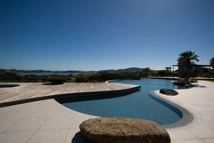 Curved infinity edge pool flows with nature — Mayfair Pools & Spas NZ ...